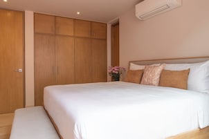 Quarto com cama grande, guarda-roupa de madeira e aparelho de ar condicionado.