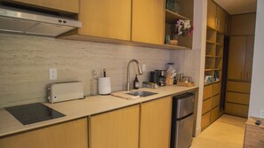 Uma cozinha moderna com armários de madeira, uma geladeira de aço inoxidável, um forno embutido e uma pia com torneira.