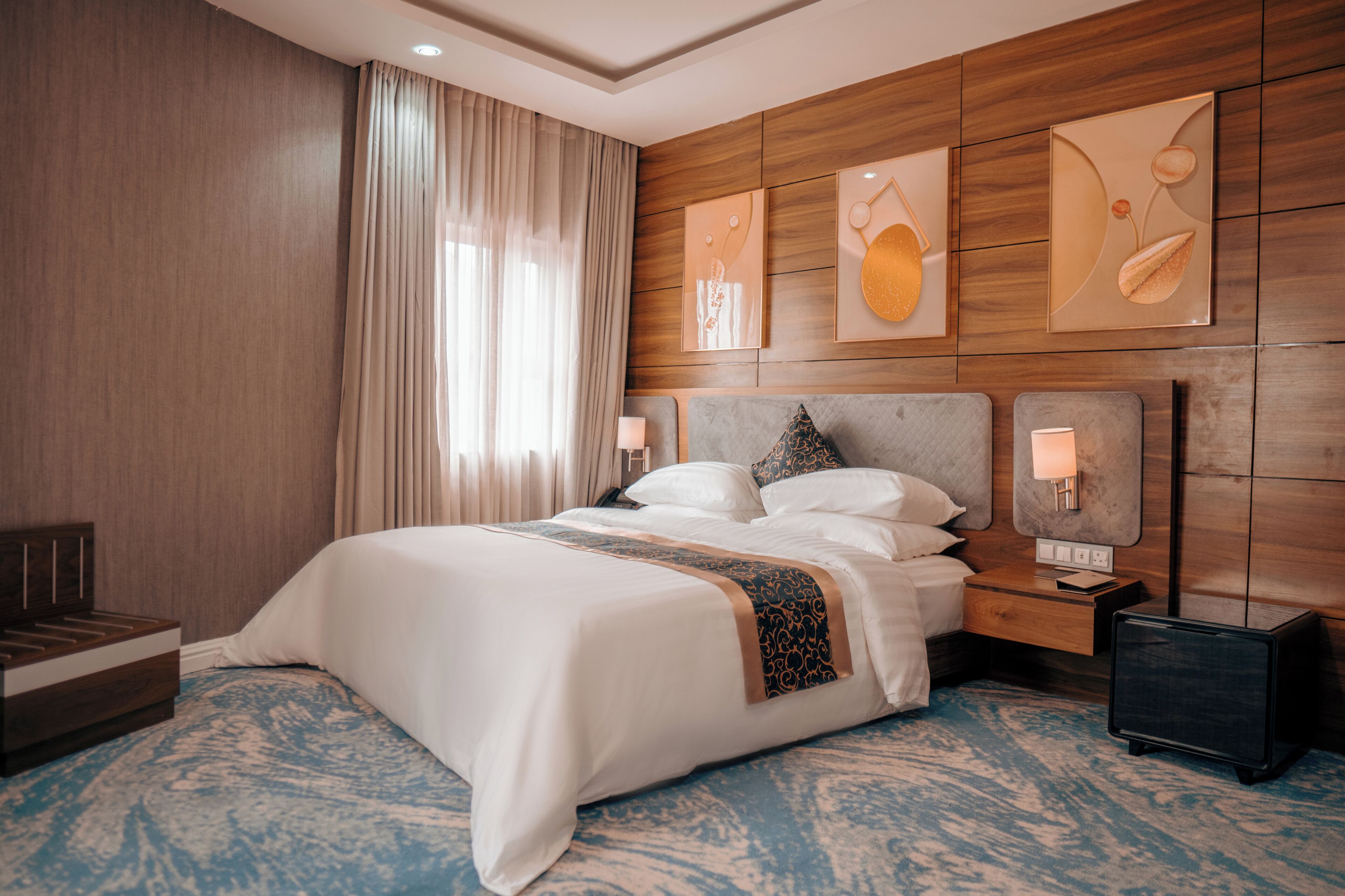 Quarto de hotel com uma cama grande, uma mesa de cabeceira, um abajur e uma obra de arte na parede.