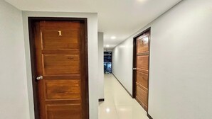 Um corredor com portas de madeira, numeradas 1 e 2, que dá acesso a quartos.