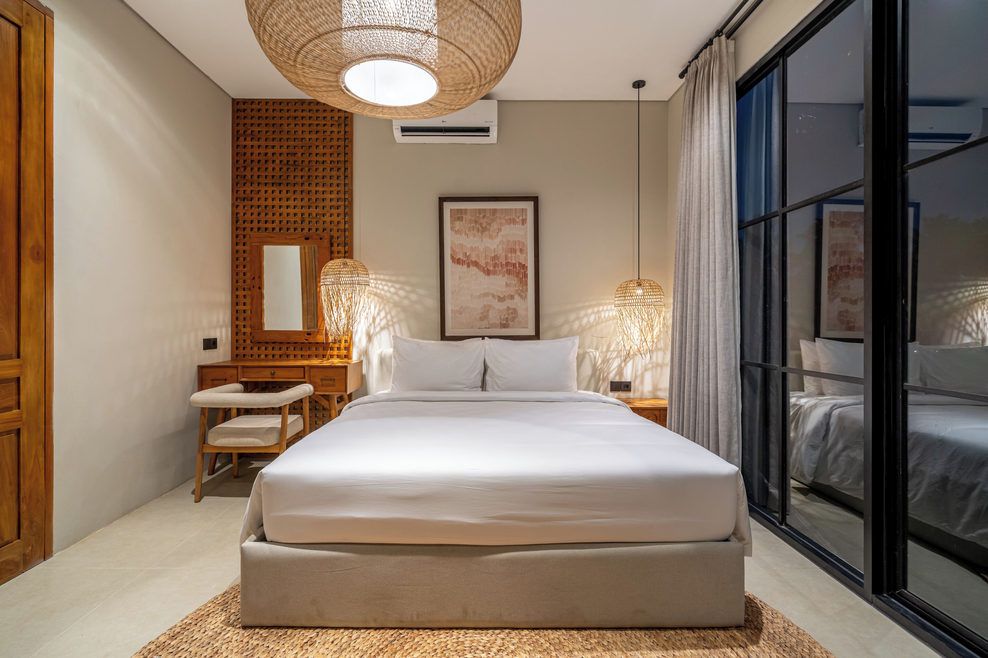 Quarto moderno com uma cama grande, uma escrivaninha de madeira, uma cadeira e uma janela ampla com vista.