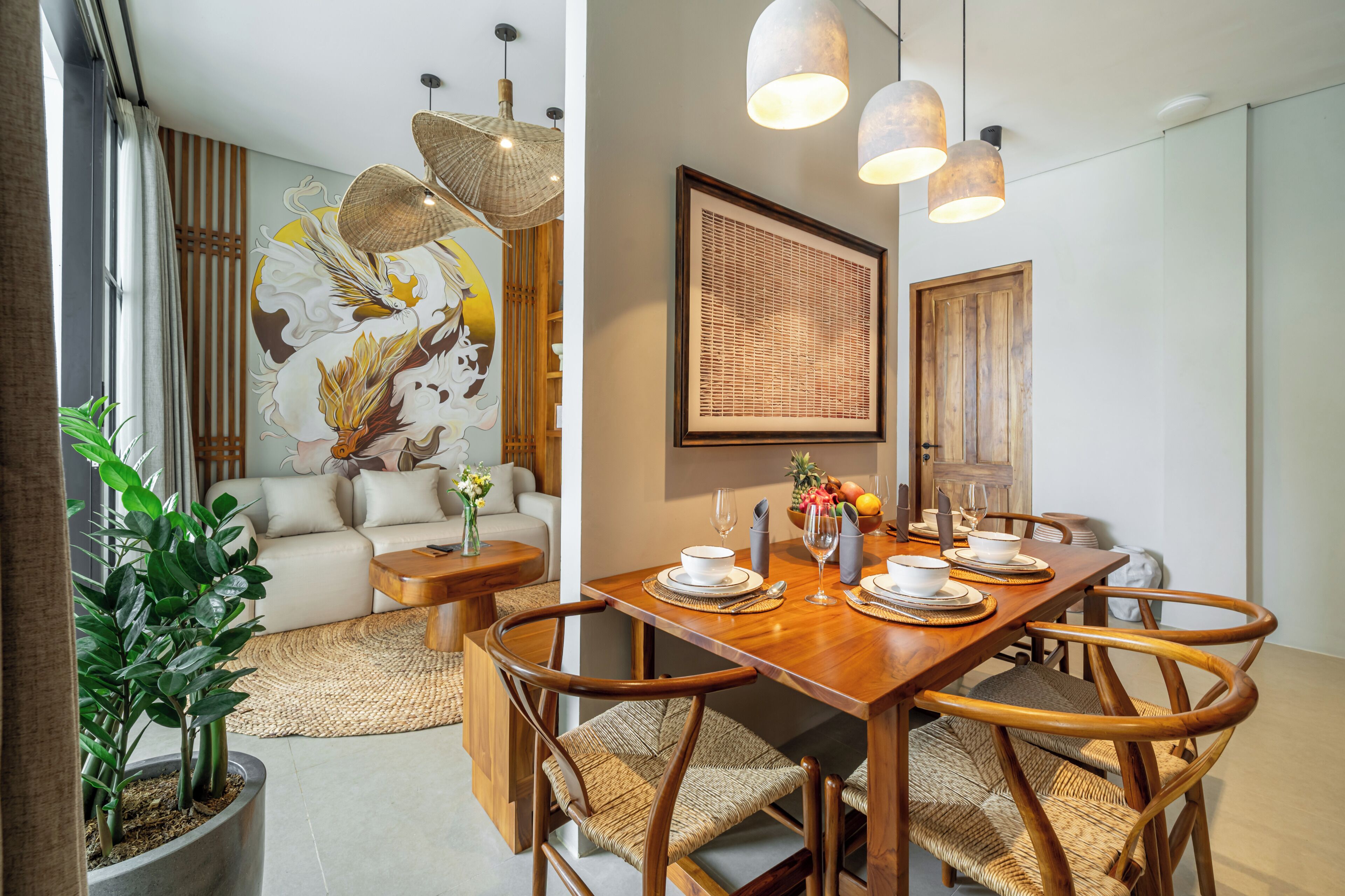 Uma área de jantar com uma mesa de madeira posta para quatro pessoas, rodeada por cadeiras de vime.