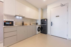 Uma cozinha compacta com micro-ondas integrado, cafeteira e máquina de lavar roupa.