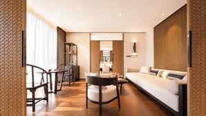 Quarto de hotel com sofá, mesa de jantar com cadeiras, um pequeno armário e um espelho.