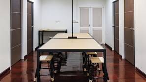 Sala de conferências com uma mesa comprida, quatro cadeiras e um suporte para projetor.