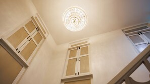 Quarto com lustre, portas de madeira e escada.