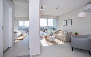 Uma sala de estar moderna com sofá, poltrona e mesa de jantar.