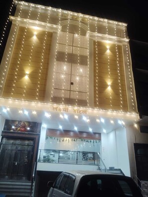 Fachada de hotel com iluminação decorativa e uma placa em idioma não português.