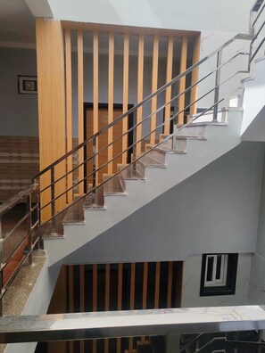 Interior com vários níveis, escada, painéis de madeira e textura de parede semelhante a mármore.