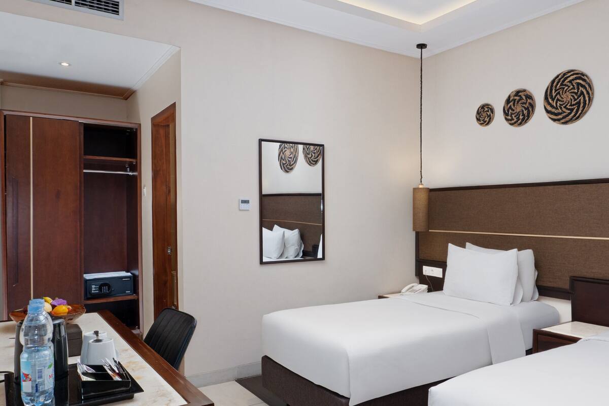 Quarto de hotel com duas camas, uma escrivaninha com cadeira, micro-ondas e minibar.
