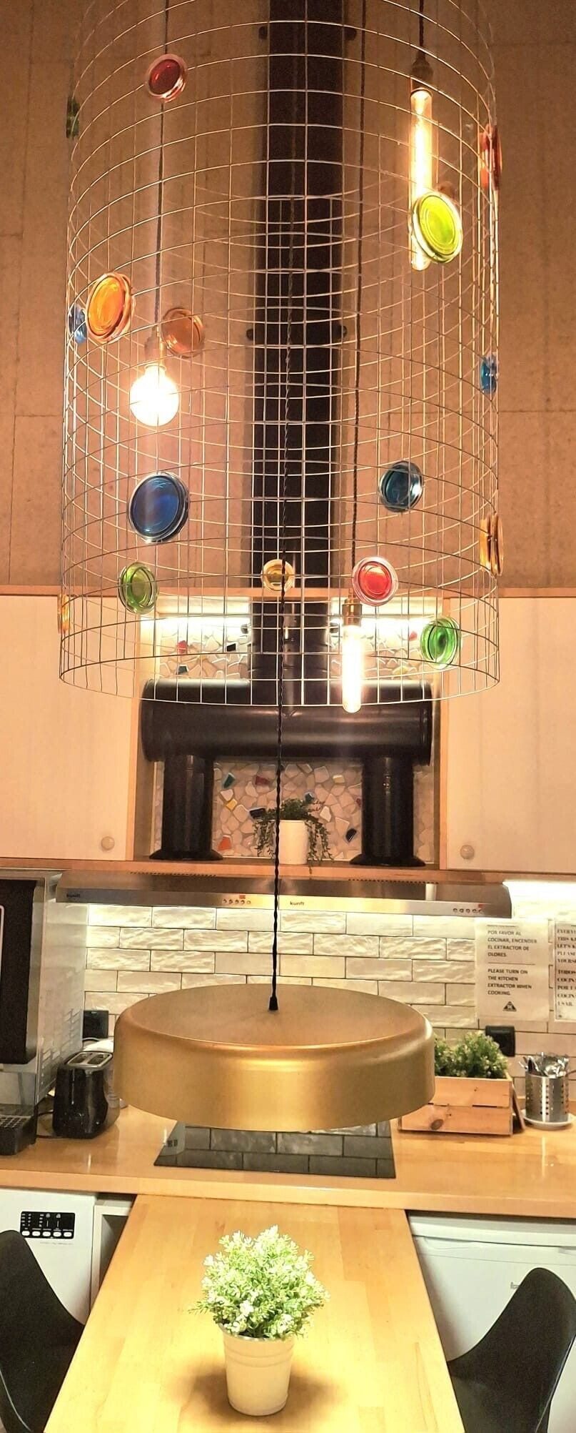 Uma cozinha com uma ilha central, um lustre com esferas de vidro coloridas e um fogão.