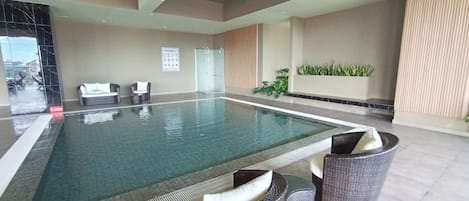 Piscina com espreguiçadeiras e uma pequena mesa.