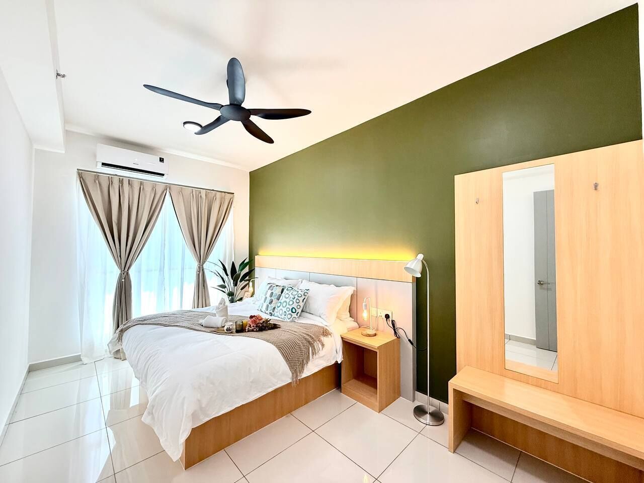 Um quarto moderno com cama, mesa de cabeceira, abajur, ventilador de teto e um espelho grande.