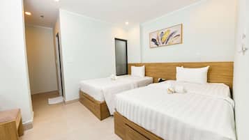 Quarto de hotel com duas camas, cabeceira de madeira, um quadro na parede e uma janela com persianas.