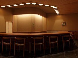 Uma área de bar com um balcão comprido e várias cadeiras.