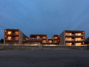 Um edifício moderno de vários andares, com varandas e amplas janelas, localizado à beira da água.