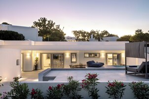 Uma casa moderna com um pátio, área de estar externa e piscina.