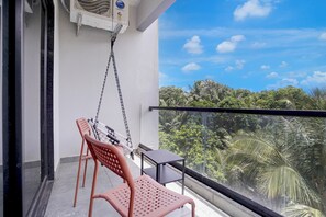 Uma varanda com uma cadeira suspensa, uma mesinha e vista para muita vegetação.