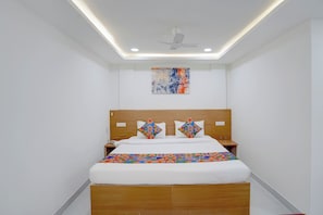 Quarto com uma cama, ventilador de teto, mesa de cabeceira e um quadro pendurado na parede.