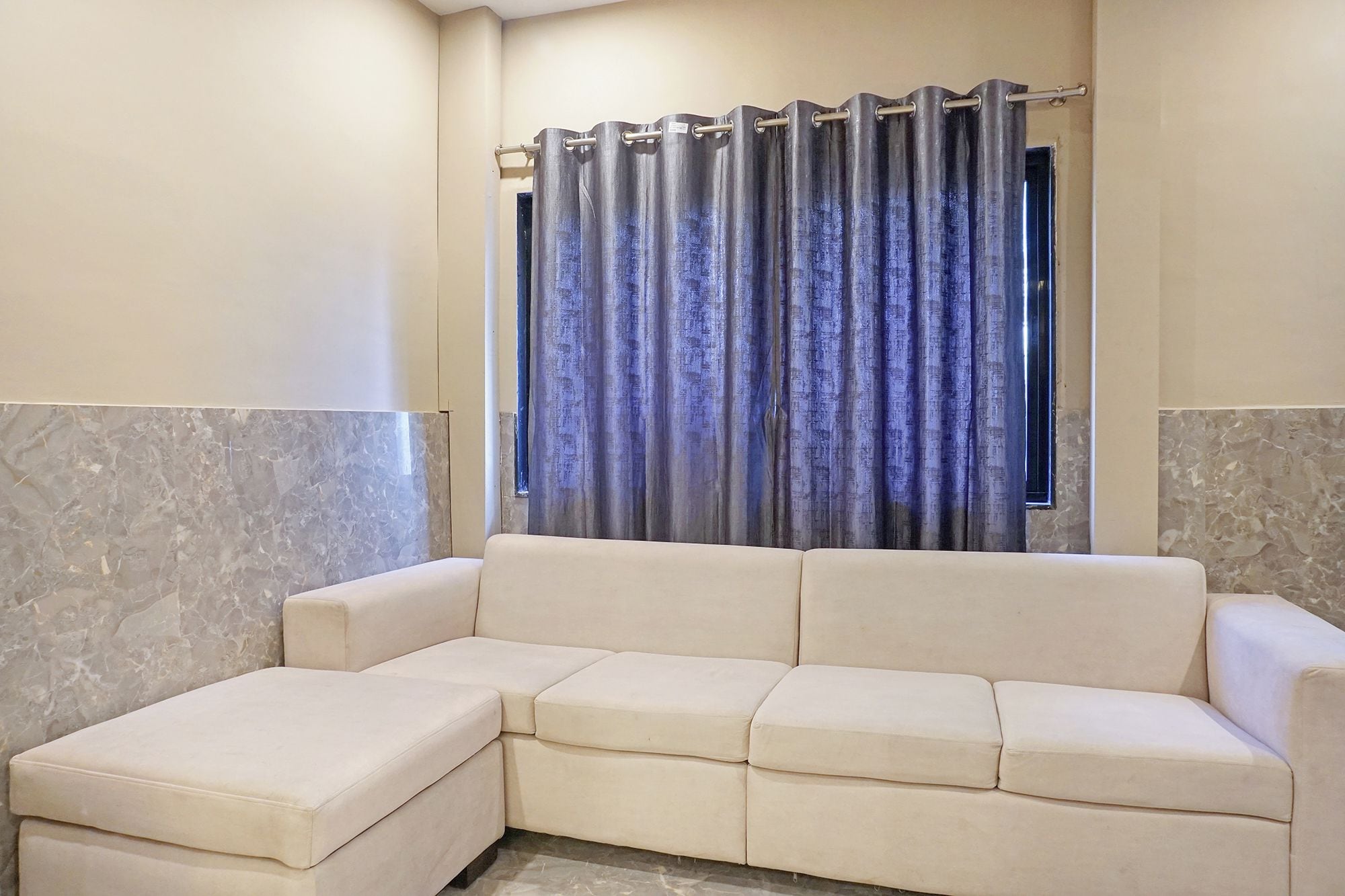 Um sofá de canto com janela e cortinas.