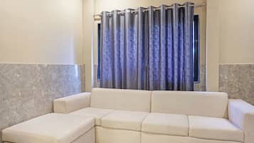 Um sofá de canto com janela e cortinas.