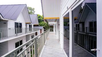 Um corredor com galeria coberta ligando vários edifícios, cada um com varanda e sinal de saída de incêndio.