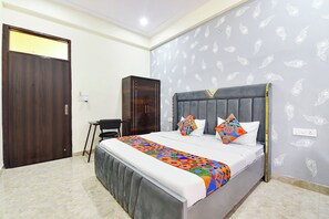 Quarto com cama, guarda-roupa, cadeira e parede estampada.