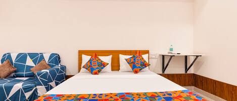 Quarto de hotel com cama, sofá, uma mesinha e uma tomada.