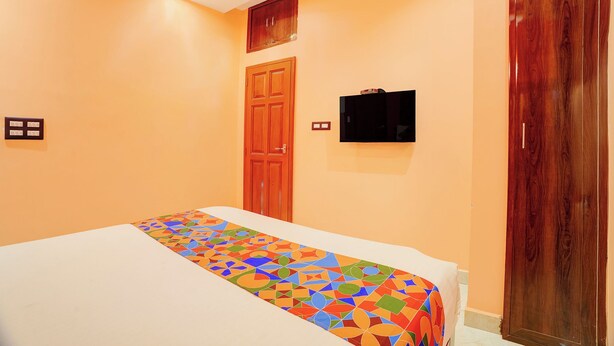 Quarto com cama, televisão e guarda-roupa de madeira.