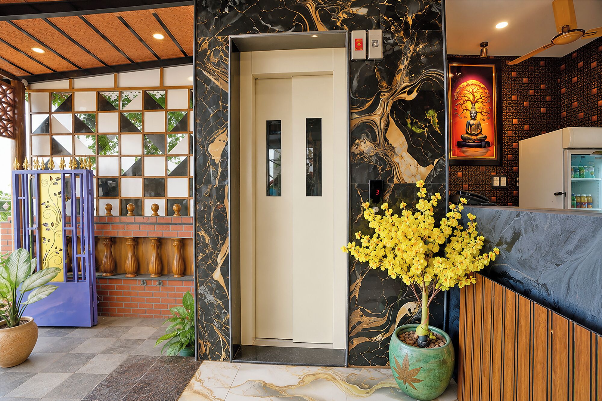 Uma área de recepção com parede de mármore, uma planta em vaso e um painel digital.