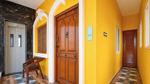 Um corredor com porta de madeira, um banco e piso ladrilhado.