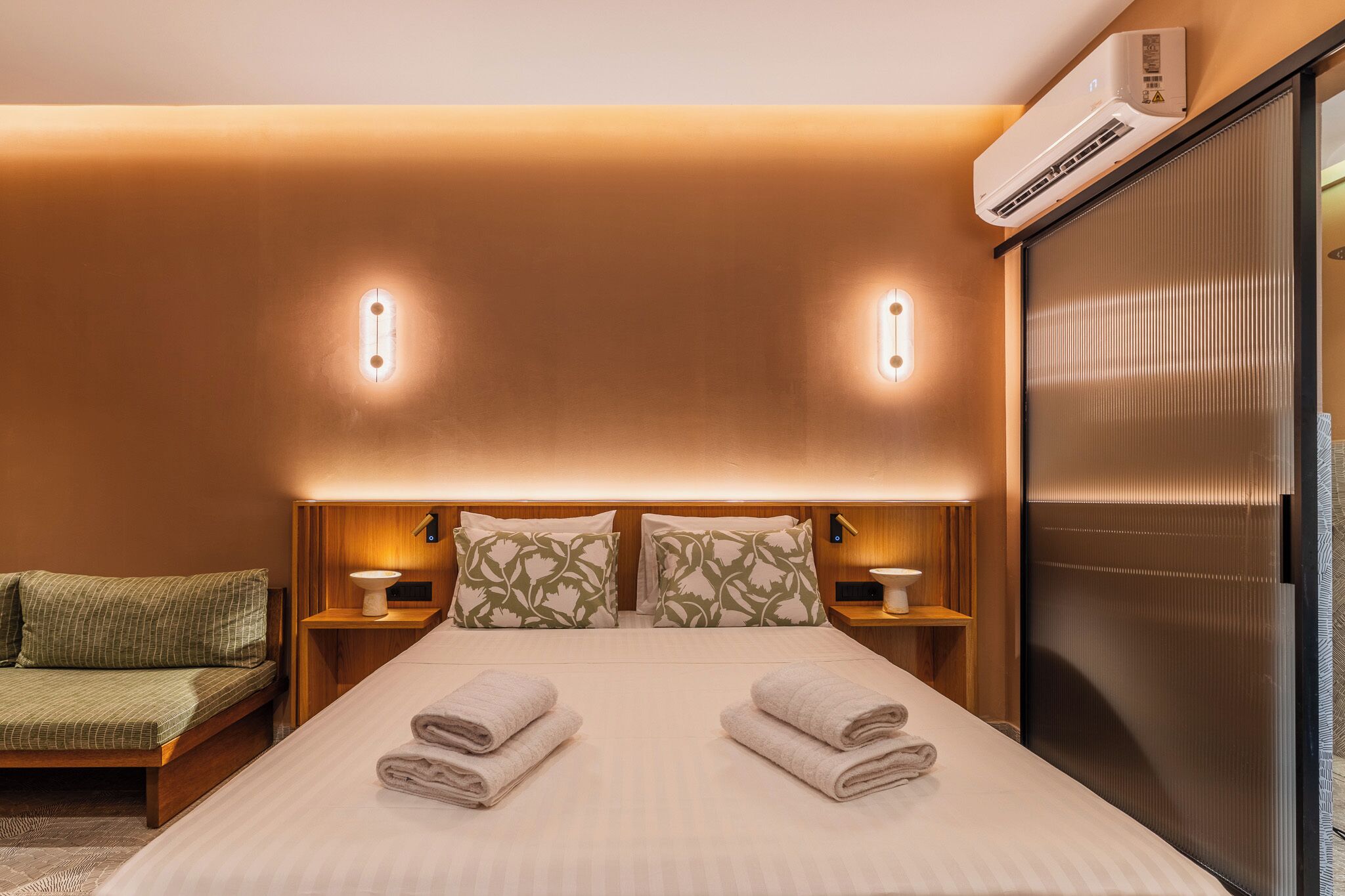 Quarto de hotel com cama, mesas de cabeceira, ar condicionado e porta deslizante.