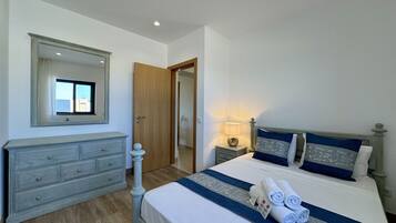 Quarto de hotel com cama, penteadeira, espelho e mesa de cabeceira com abajur.