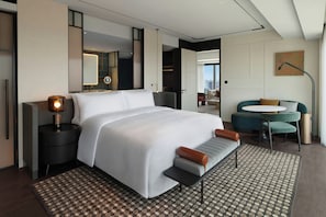 Quarto de hotel moderno com cama grande, mesa de cabeceira e escrivaninha com cadeira.