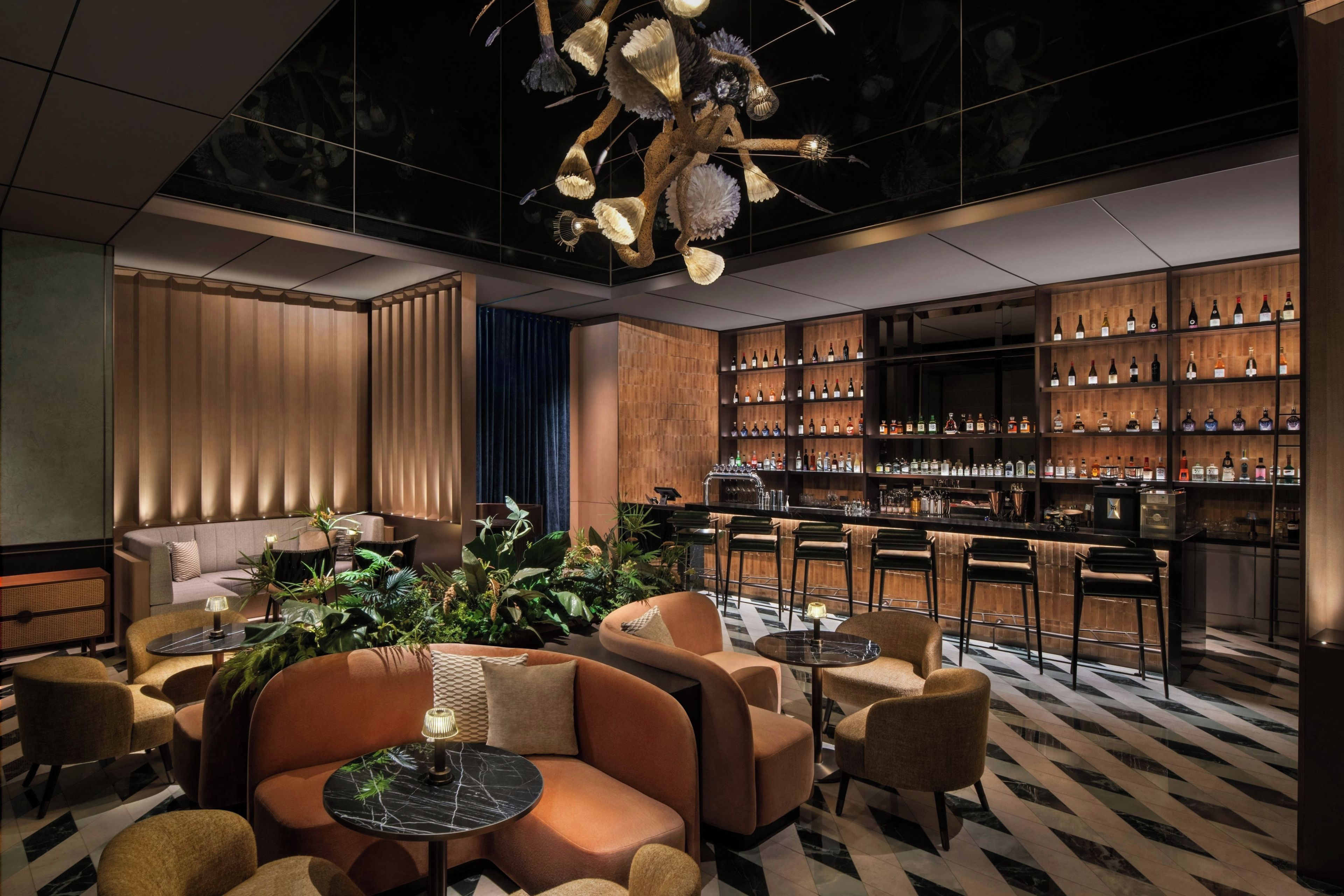 Área de bar moderna com assentos e diversas garrafas de bebidas.