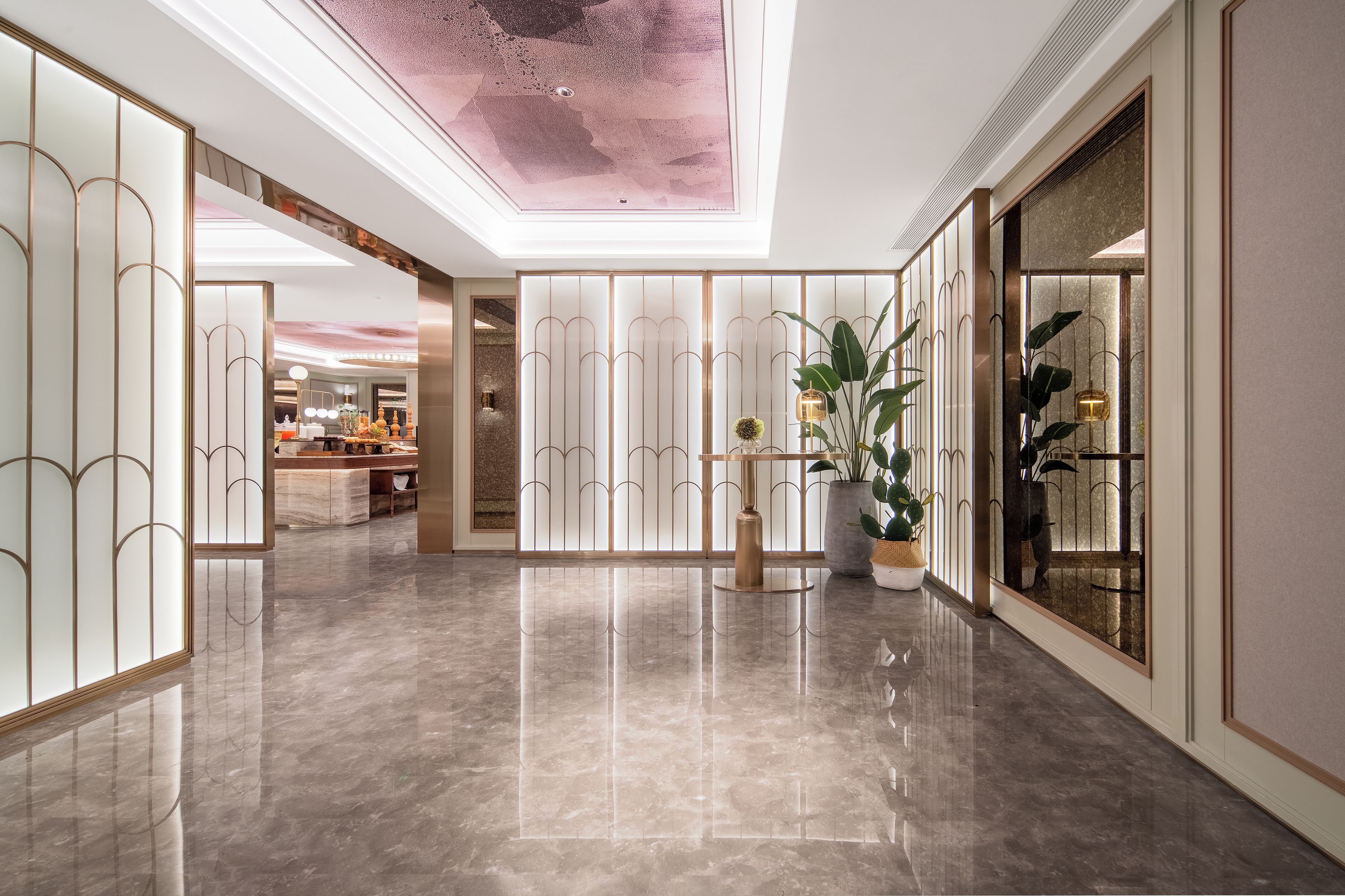 Um hall amplo com piso de mármore polido, teto com claraboia e área de recepção ao fundo.
