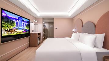 Quarto de hotel com uma cama grande, televisão fixada na parede e um armário de madeira.