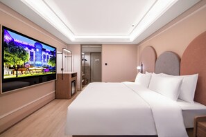 Quarto de hotel com uma cama grande, televisão fixada na parede e um armário de madeira.