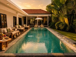 Uma área à beira da piscina com espreguiçadeiras, uma mesa de jantar e vista para a piscina.