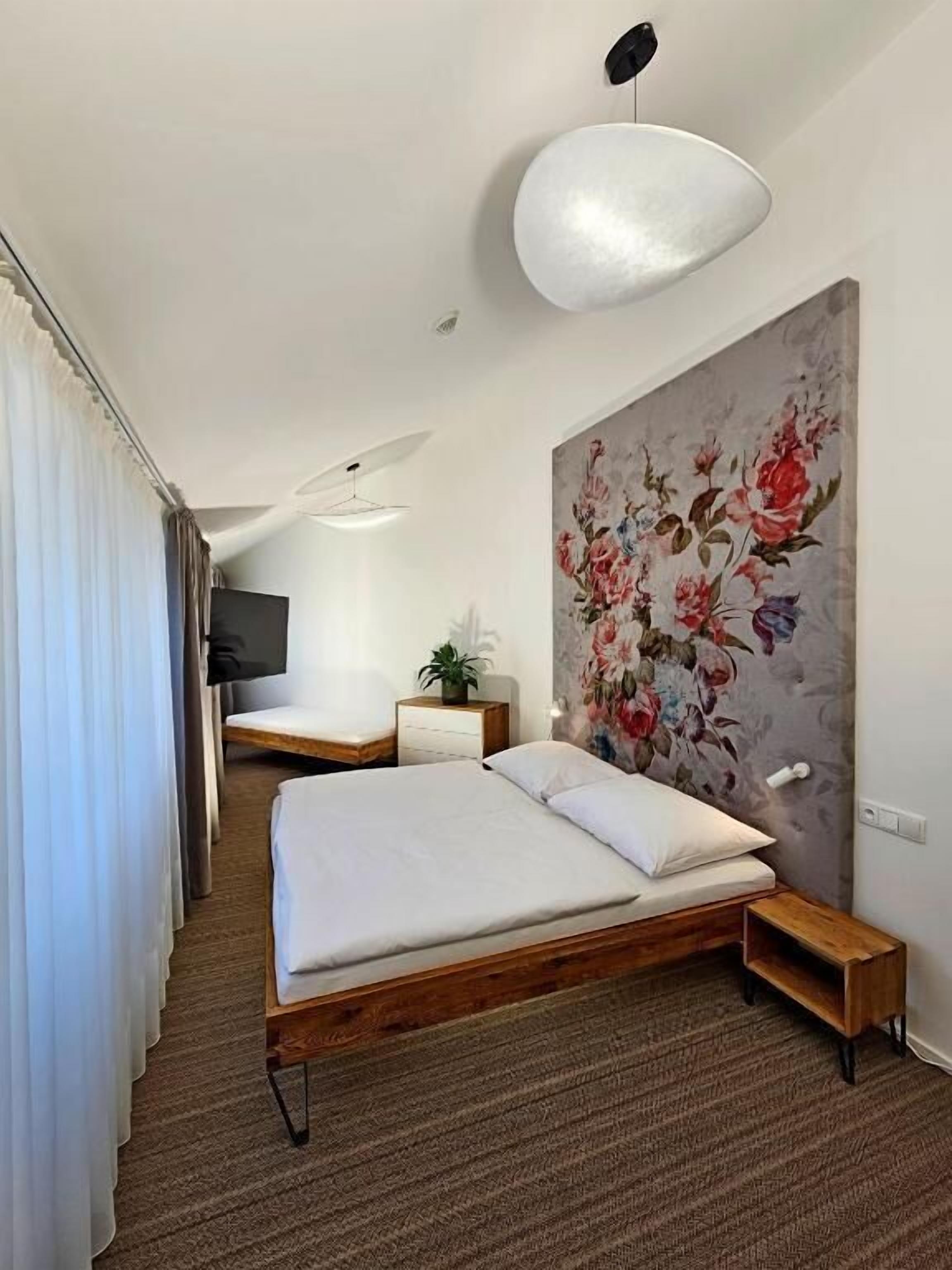 Quarto de hotel com cama, mesa de cabeceira e uma grande obra de arte floral na parede.