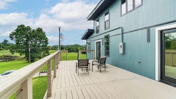 Um terraço com área de estar ao ar livre, guarda-corpo e vista para uma paisagem verde.