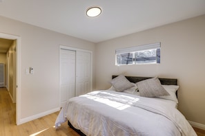 Quarto com cama, janela, porta e luminária.