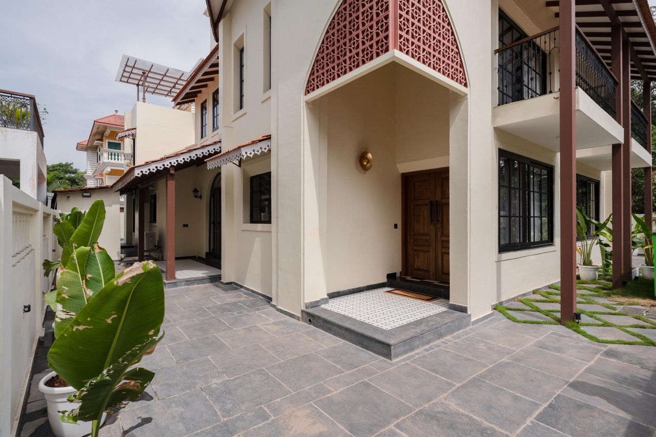 Edifício residencial com entrada coberta, planta em vaso e área de pátio com ladrilhos.