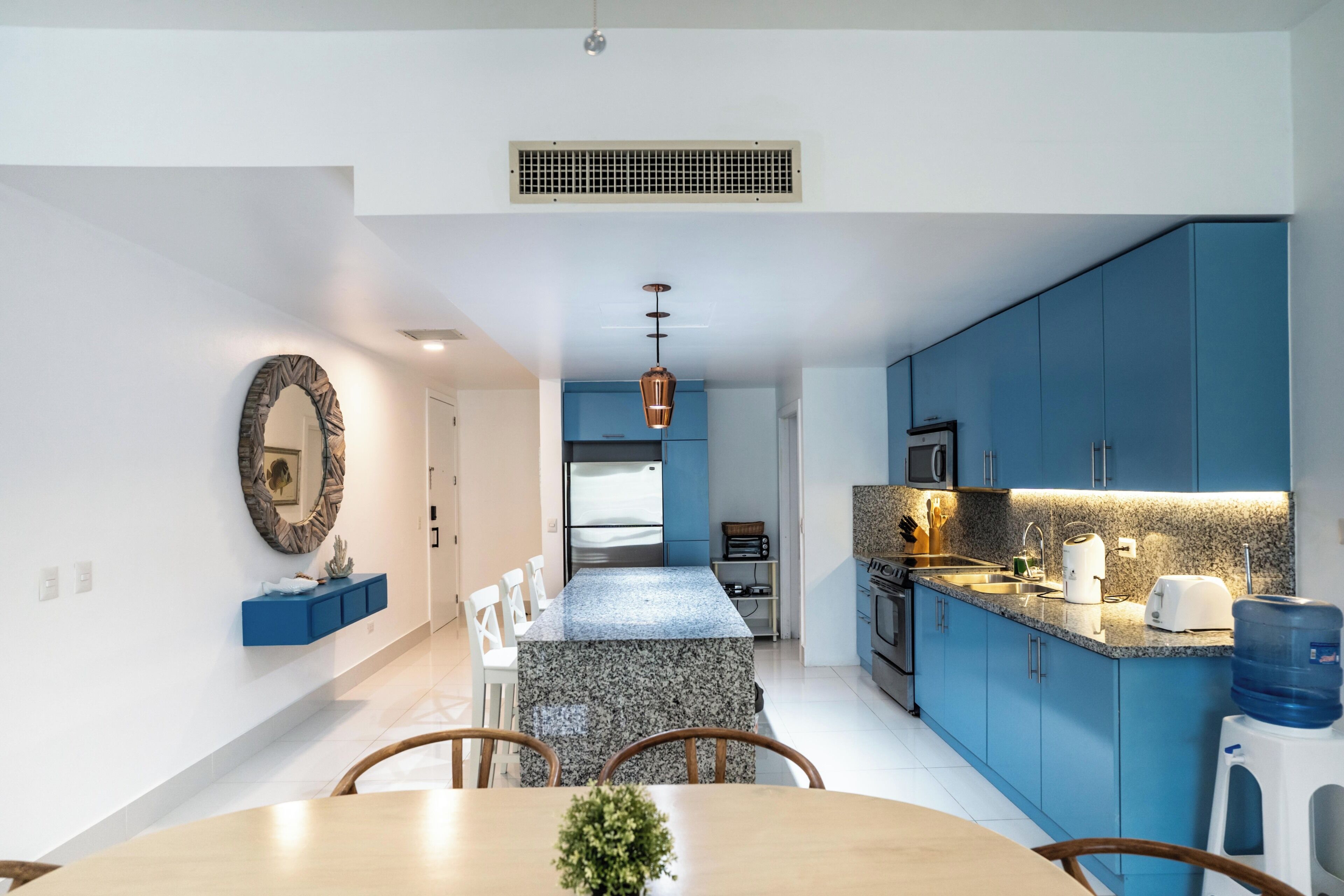 Cozinha moderna com armários azuis, bancada de granito e uma ilha central.