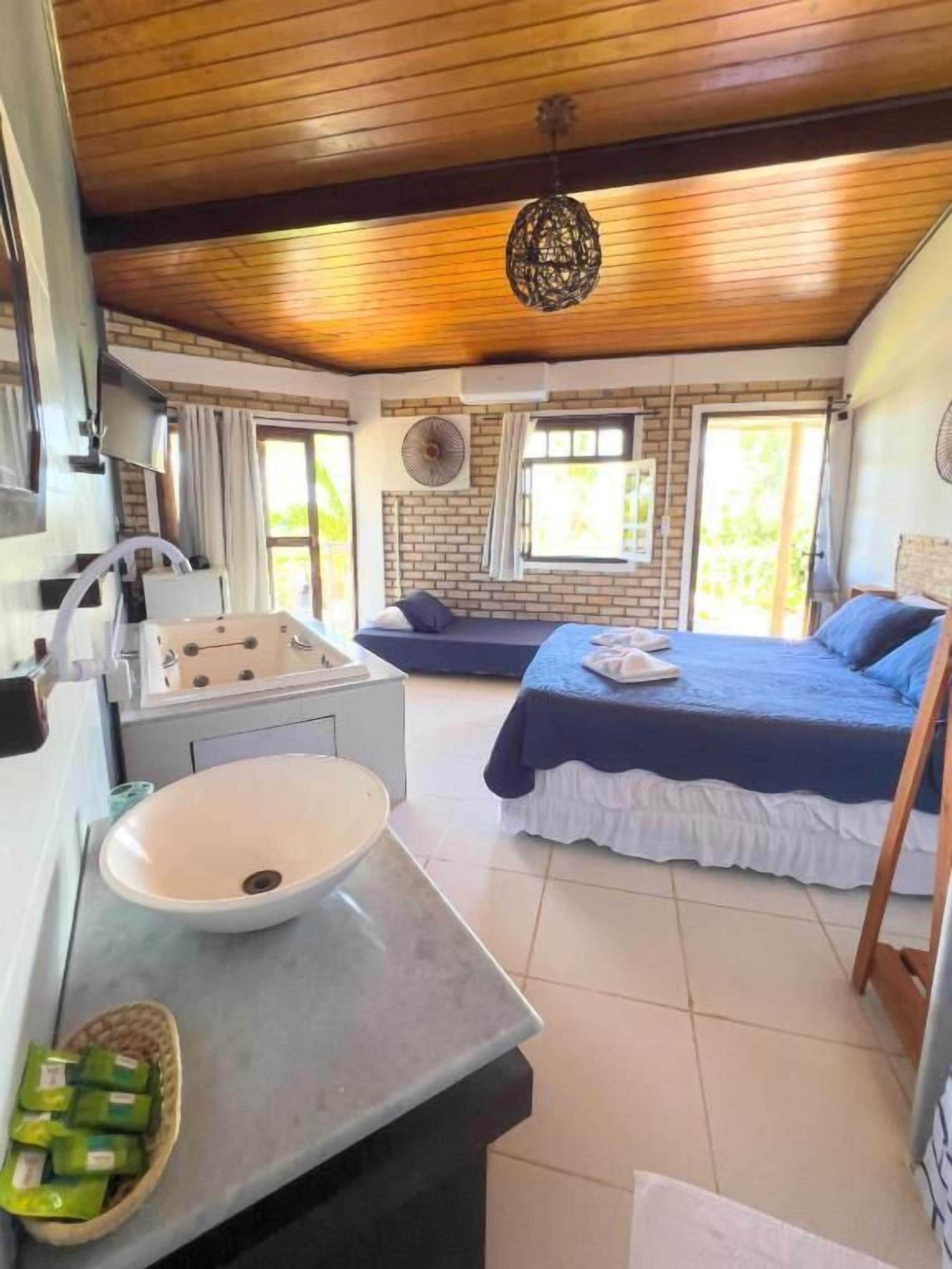 Quarto com cama, pia e janela.