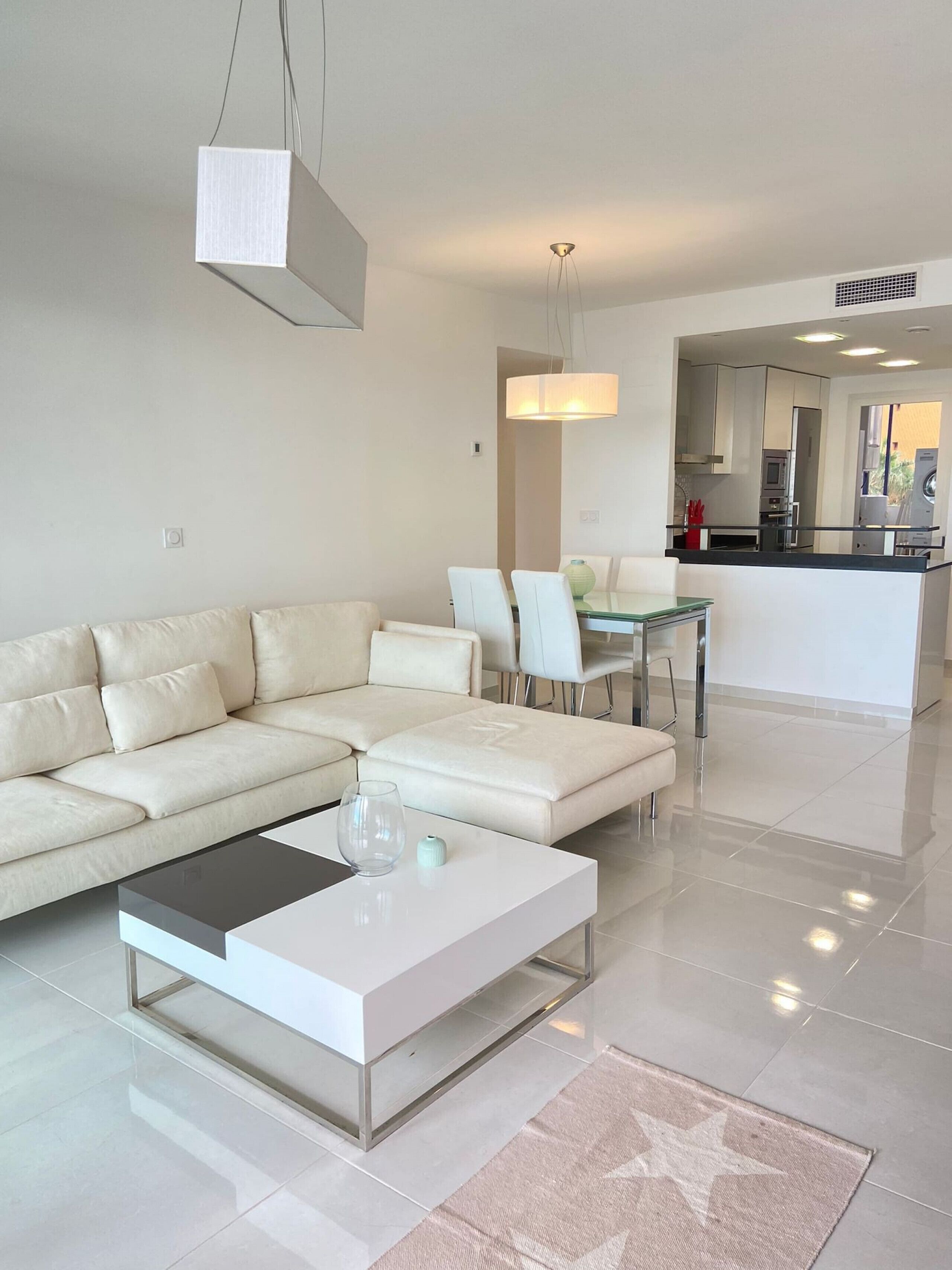 Uma sala de estar moderna com um sofá seccional, uma mesa de centro e uma área de jantar com cadeiras e uma mesa.