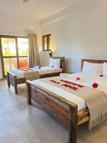 Quarto de hotel com duas camas de madeira, uma janela grande e uma varanda.