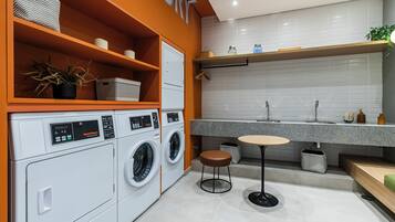 Uma lavanderia moderna com máquina de lavar, secadora e uma pequena mesa.