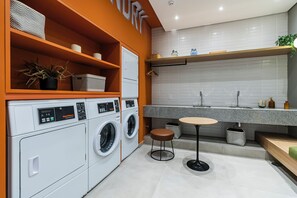 Uma lavanderia moderna com máquina de lavar, secadora e uma pequena mesa.
