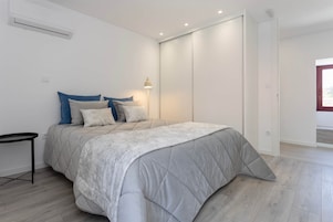 Um quarto moderno com cama, mesa de cabeceira e abajur.